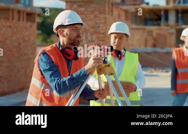 Young man engineer surveyor takes measures with theodolite stand and ...