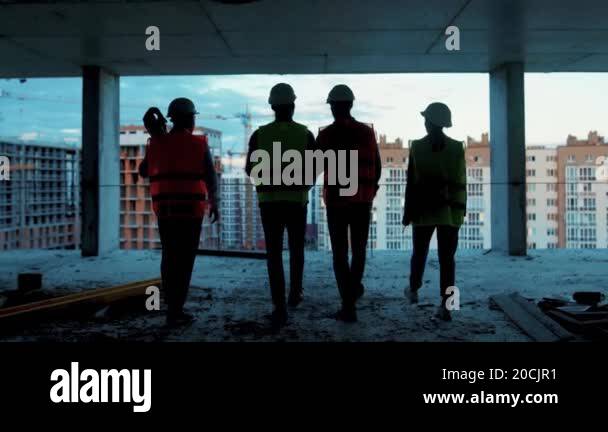 View of shot back builders engineers workers in hard hat team walking ...