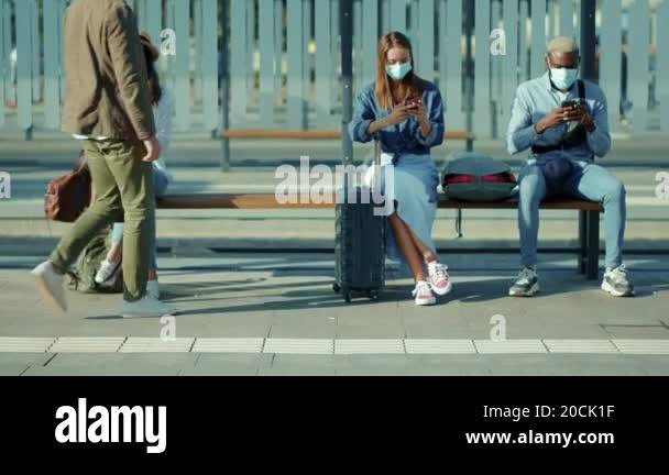 On bus stop mixed-races young male and female people in medical masks ...