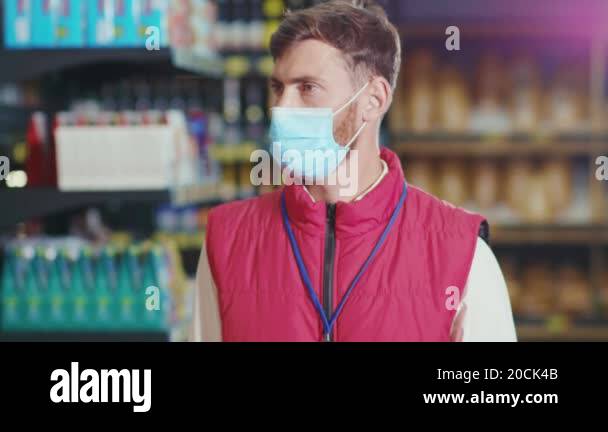 Portrait young seller man with mask in supermarket look camera ...