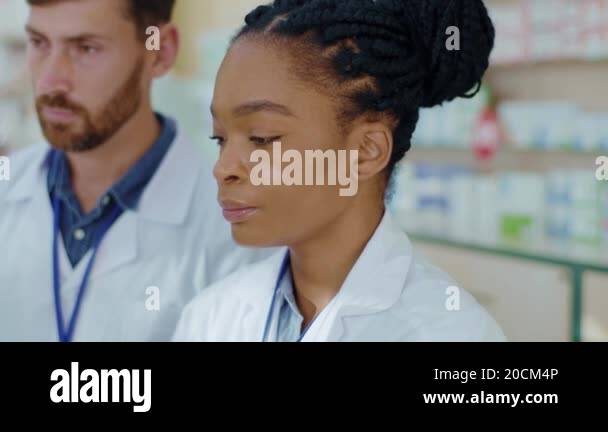 Two cooperative mixed-race young people pharmatists learning ...