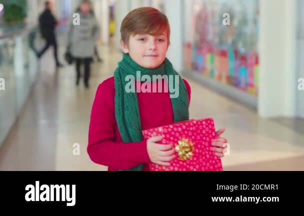 Happy boy walk in the shopping mall put in cart Christmas present boxes ...