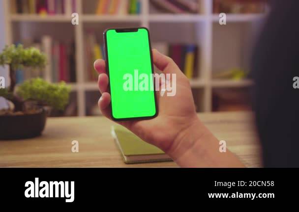 NEW YORK - May 19, 2019: Close up hands man hold phone with vertical green screen use touch ...