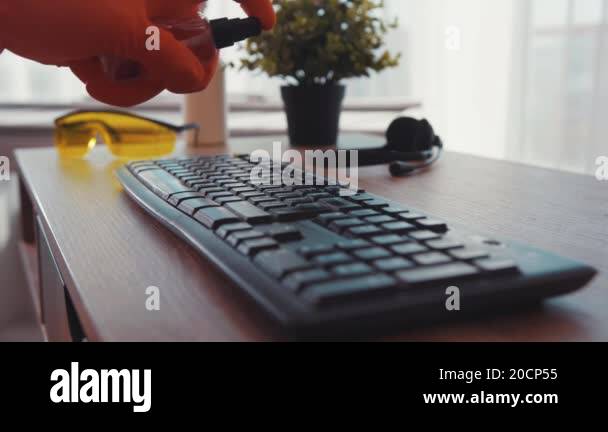 On table hands disinfecting laptop keyboard with antiseptic spray and ...