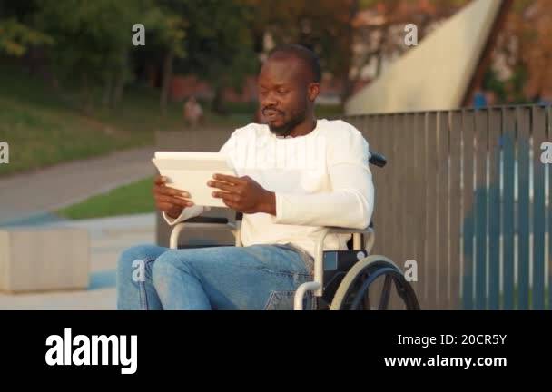 Close up young african american man on a wheelchair with tablet ...