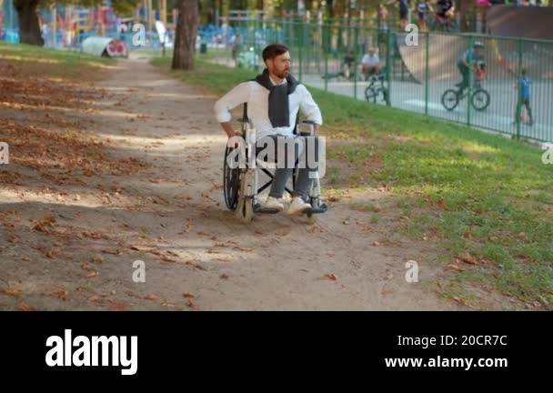 Young portrait serious handsome disabled man rides in wheelchairat at ...