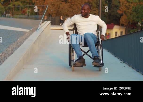 Happy handsome disabled man rides in wheelchair at sunlight smiling ...