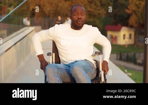 Portrait of happy handsome disabled man rides in wheelchair at sunlight ...