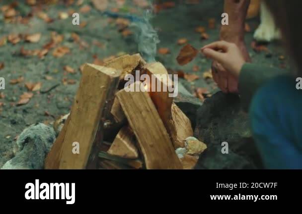 Close up hands father and daughter in the woods sets up campfire sticks ...