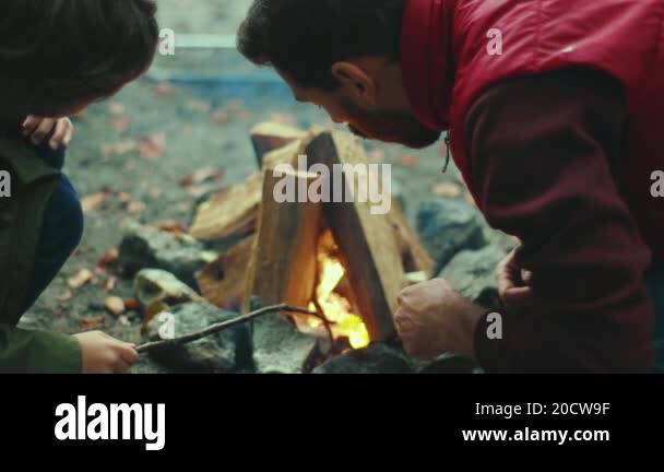 Close up hands father and son in the woods sets up campfire sticks ...