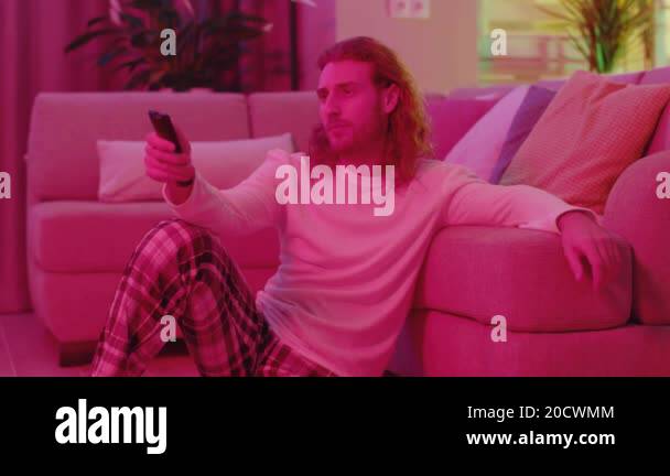 Bored caucasian sleepy guy watching Tv in the evening browsing channels ...