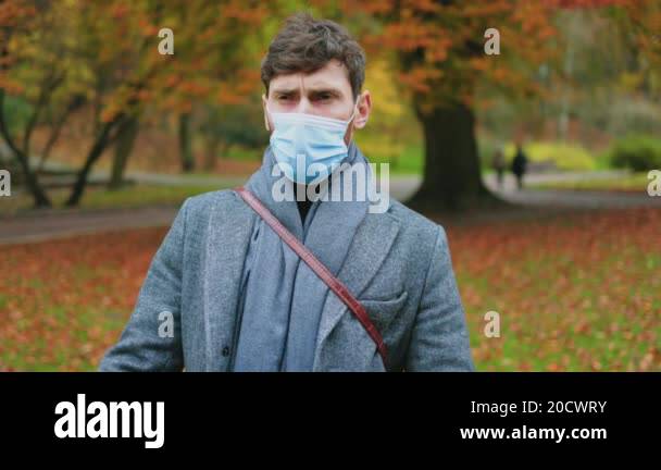 Close up sick young man with sad face and a protective mask coughs ...