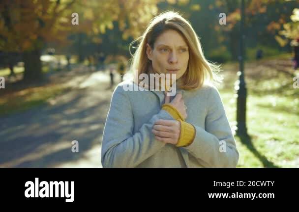 At sunlight sick young woman look around walking feel cold in autumn ...