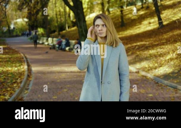 Sick young woman having headache feel cold coughs stand in autumn park ...