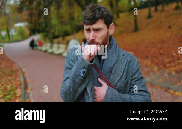 Tired sad sick young man stand having headache coughs sneezes look at ...