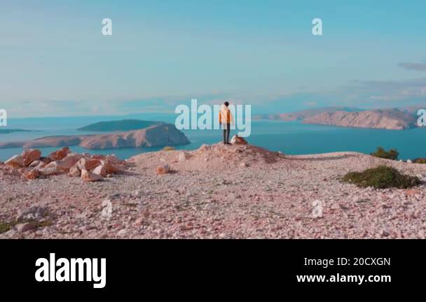Horizontal back shooting of young man in yellow hoodie standing on top ...