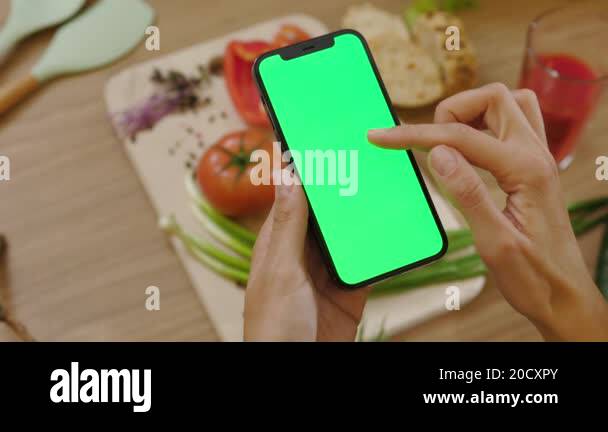 Woman hands hold phone with vertical green screen on vegetables on ...