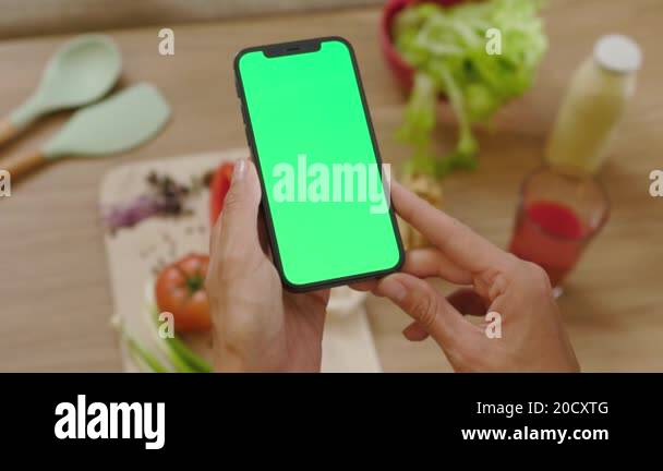 Close up hands woman hold phone with vertical green screen on ...