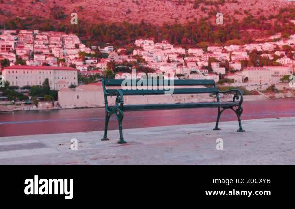 Close up empty bench view on sea channel and old town at sunset. Water ...