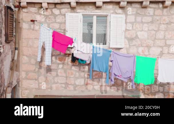 Close up hanging clothes moved by the wind from a window of old ...