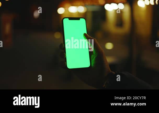 Shot of hands man use phone with vertical green screen stand at night ...