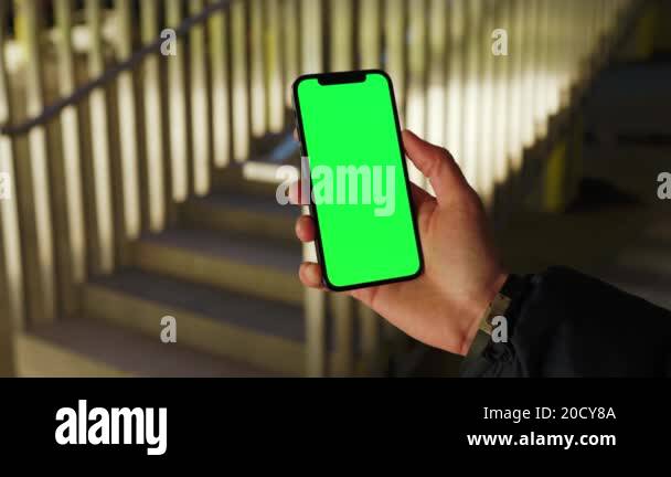 Close up young hands man holding and touching the phone with vertical green screen in the ...