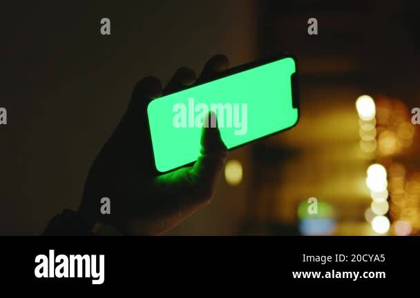 Hands man use phone with vertical green screen stand at night city ...