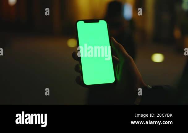 At night young hands man use phone with vertical green screen stand ...