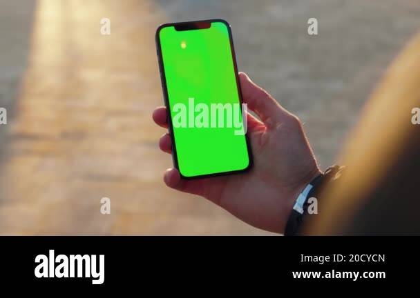 NEW YORK - December, 19 2020: Close up man young hand using touch phone with vertical green ...