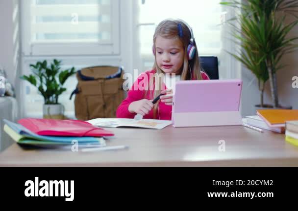 Cute child girl use headphones and tablet computer lesson online at ...