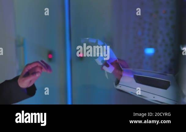 In dark room man hand touch finger with a cybernetic robot through the ...