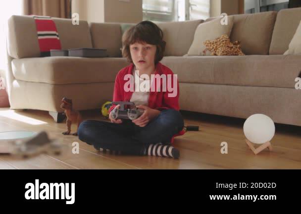 Adorable caucasian teen boy flying interactive small drone in living ...
