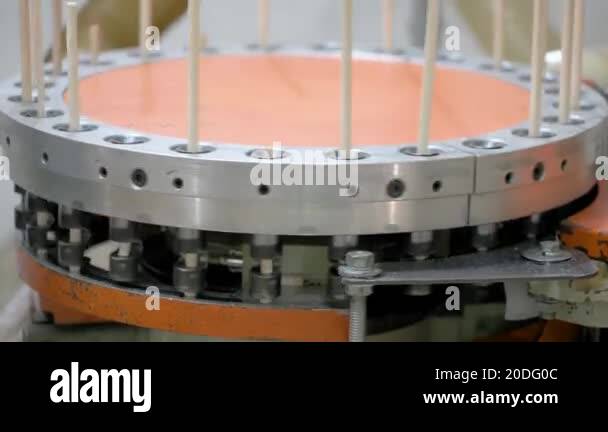 A machine processes wooden dowels, arranging them vertically in a ...