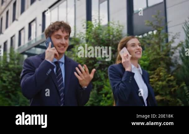 Cheerful businesspeople talking smartphones walking urban area closeup ...