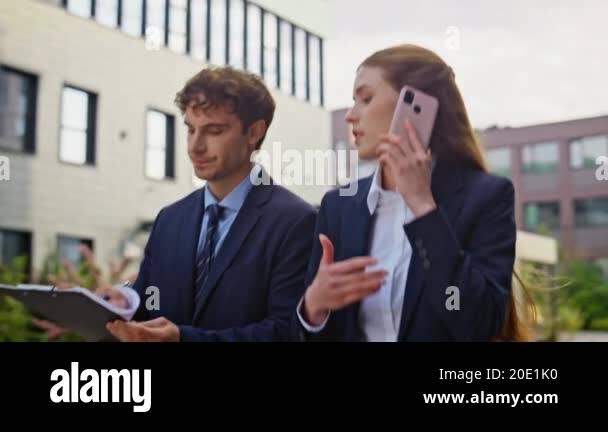 Lady boss talking cellphone walking with man secretary at city street ...