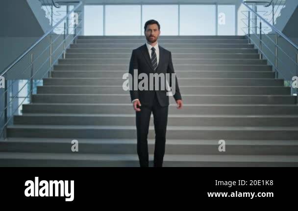 Smiling manager inviting to office standing at modern staircase in ...