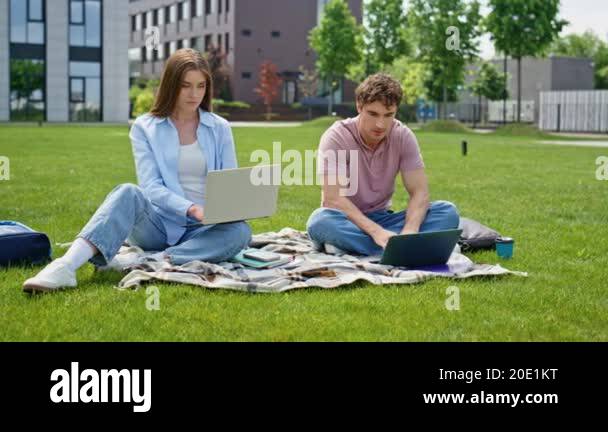 Man woman working in park together looking laptops. Two students ...