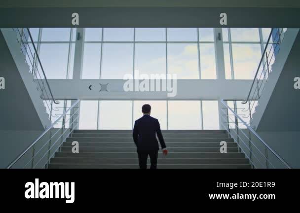 Executive walking up stairs inside sleek modern office building ...