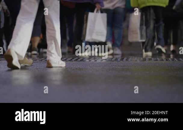 A vibrant and bustling city street showcases an array of shoppers walking through the rain ...