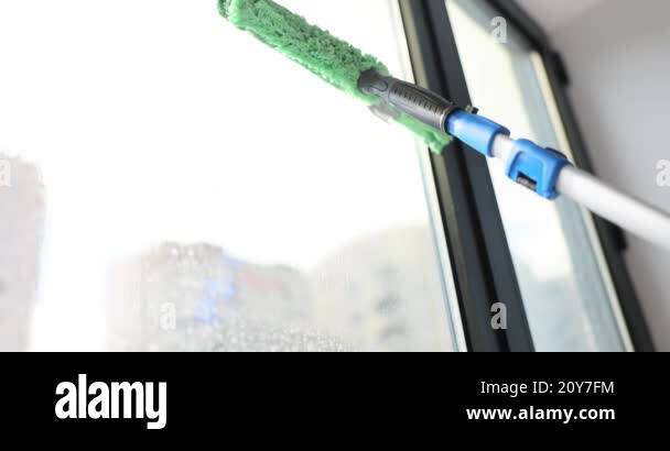 Washing windows in a high-rise building with a green scraper in an ...