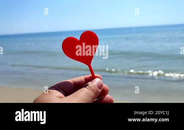 Person holding in fingers hand stick in shape red heart on background ...
