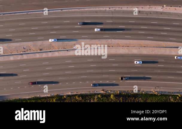 This video offers an aerial view of a busy highway with cars navigating ...