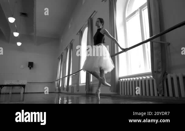Prima ballerina in white skirt stretching practicing ballet positions ...