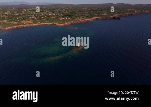 Rugged rocks and calm seas surround Faro Mangiabarche, Sardinias iconic ...