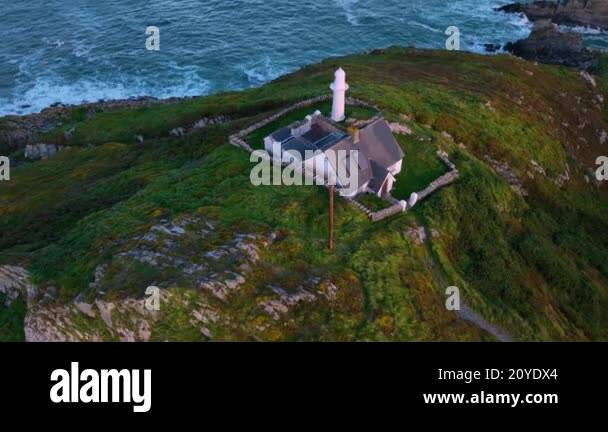Aerial. Picturesque house by the sea with lighthouse on a rocky island ...