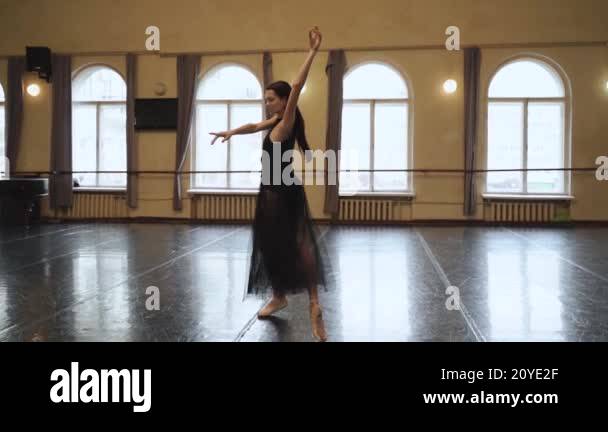 A professional ballerina shows Arabesque in front of a large window of ...