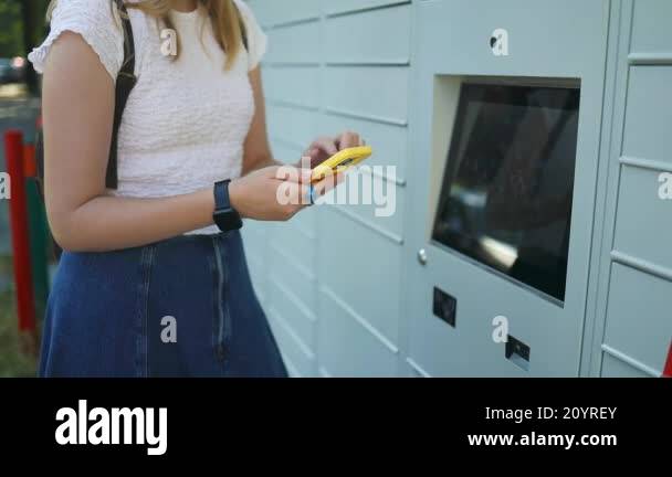 Woman using automated self service post terminal machine or locker to ...