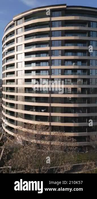 A sleek, modern residential building features curved facades and large windows, capturing ...