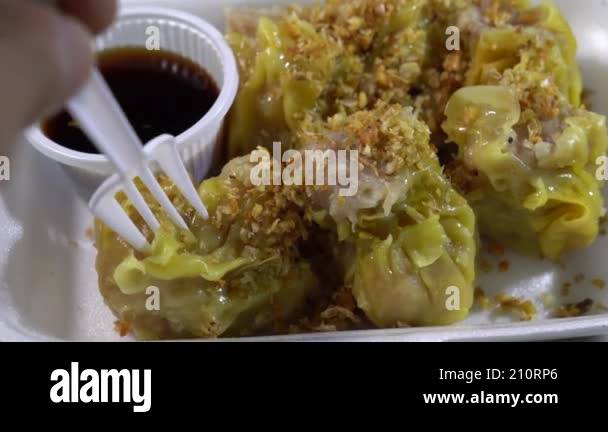 Sprinkle fried garlic over six minced pork dumplings in a white foam ...