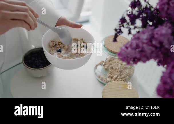 Close-up of a hand holding a bowl of granola with milk and berries ...